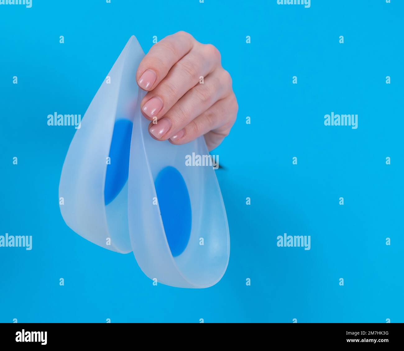 Woman holding orthopedic silicone heel pads. A woman's hand sticks out ...