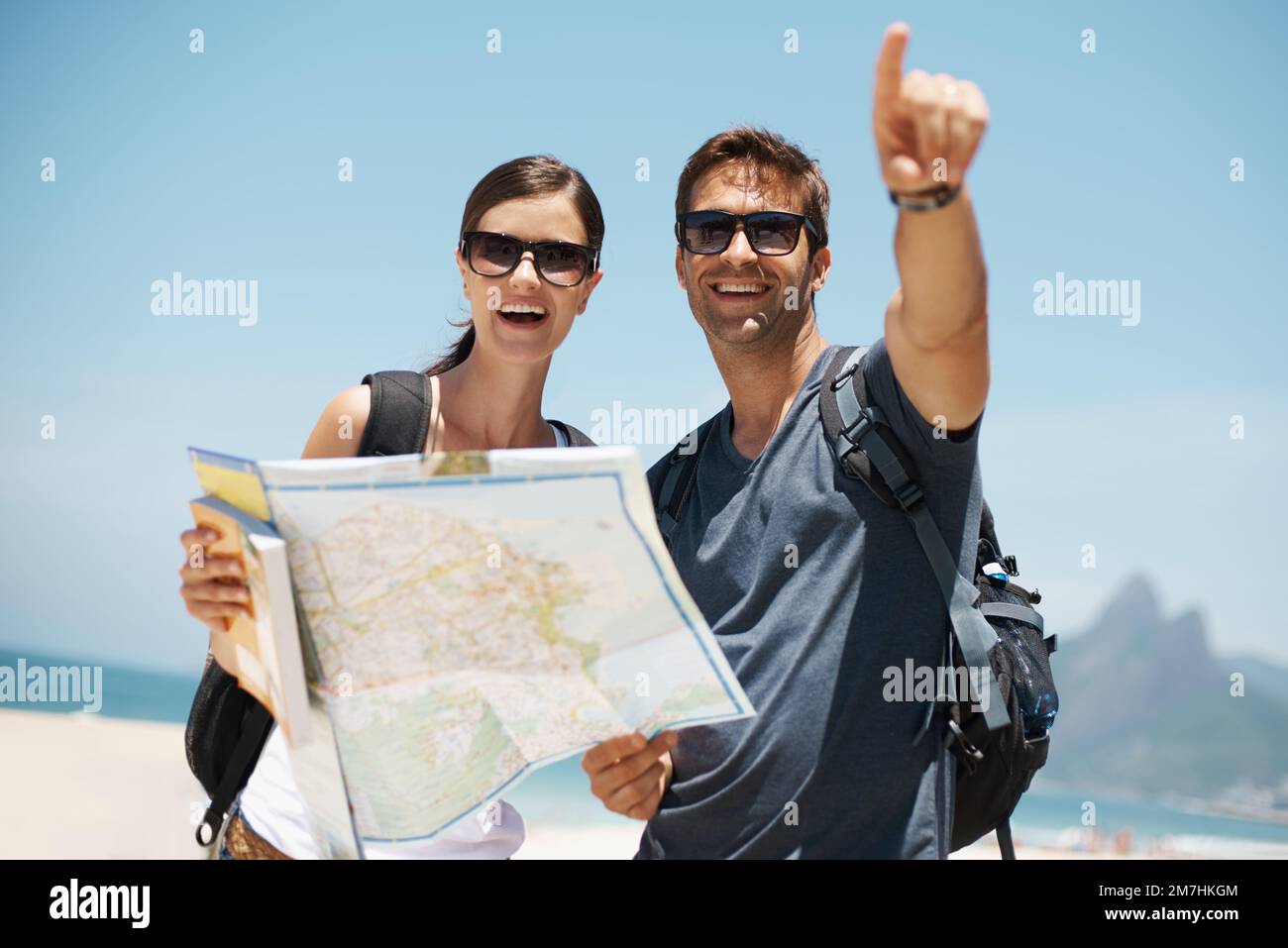 I think we should be heading that way. a young couple holding a map and ...