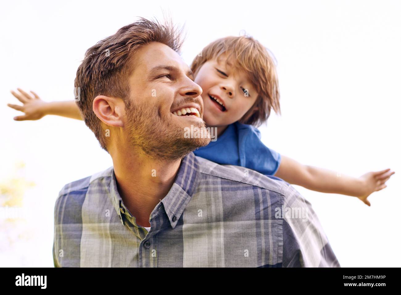 Flying like a superhero. a young father giving his son a piggyback ride ...