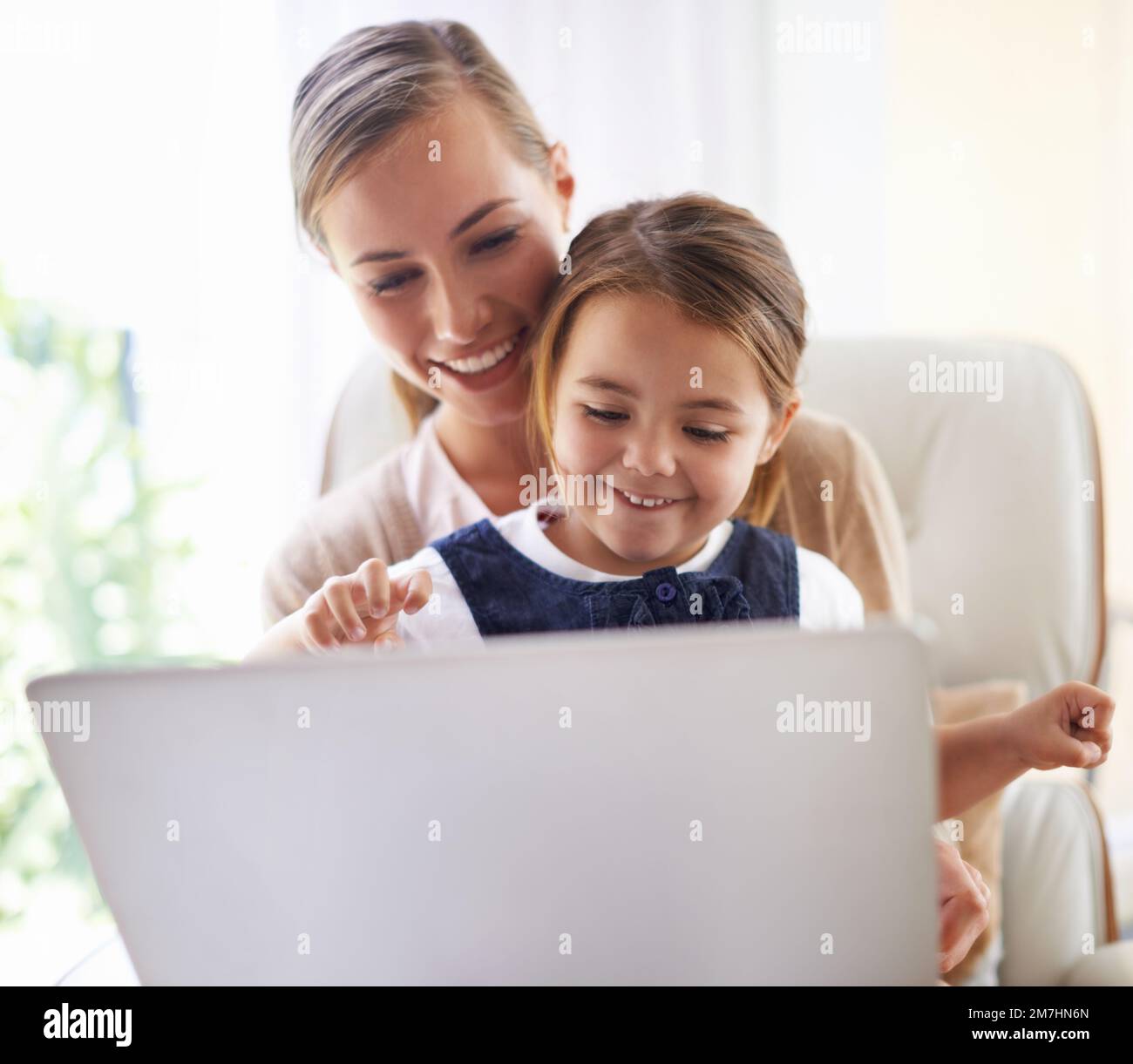 Helping her out. a mother using a laptop with her daughter Stock Photo ...
