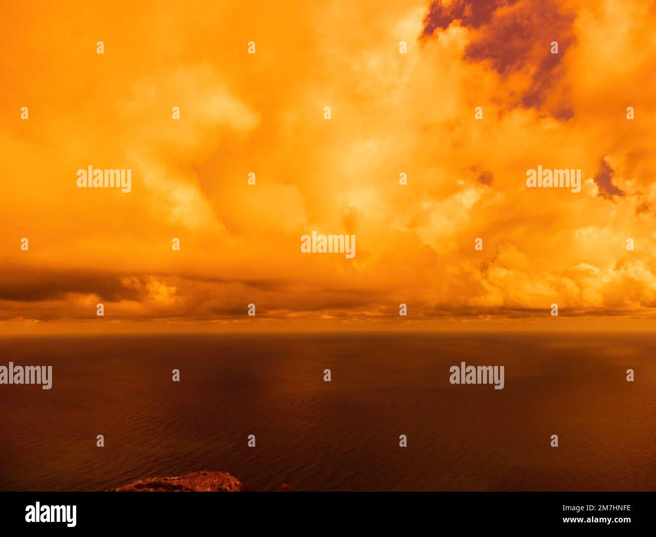 Aerial view red burning sunset over the sea with rocky volcanic cliff ...