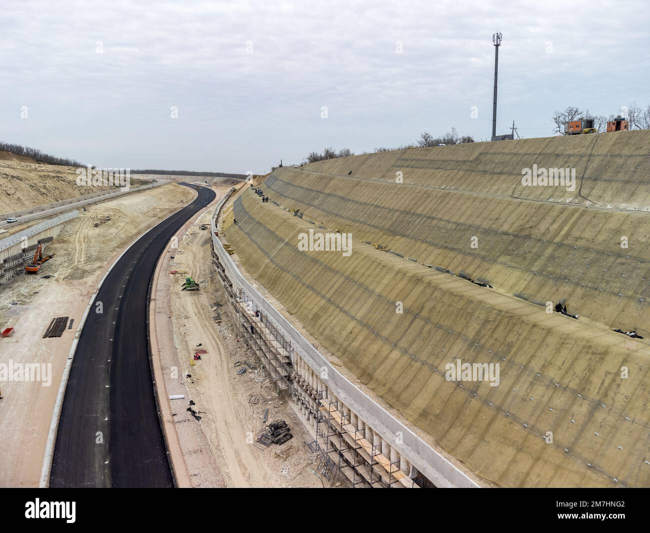 Mountain road constraction. Workers reinforce the slope over the new ...