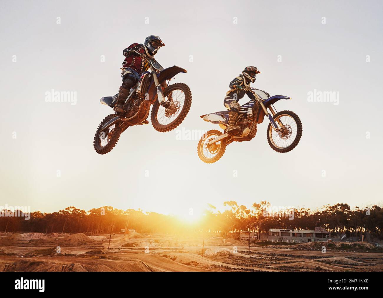 Jumping over the sunset. A shot of two motocross riders in midair ...