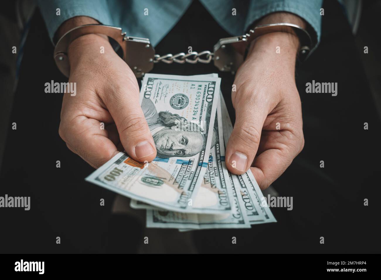 Hand with handcuffs and US dollars against dark background. concept of ...