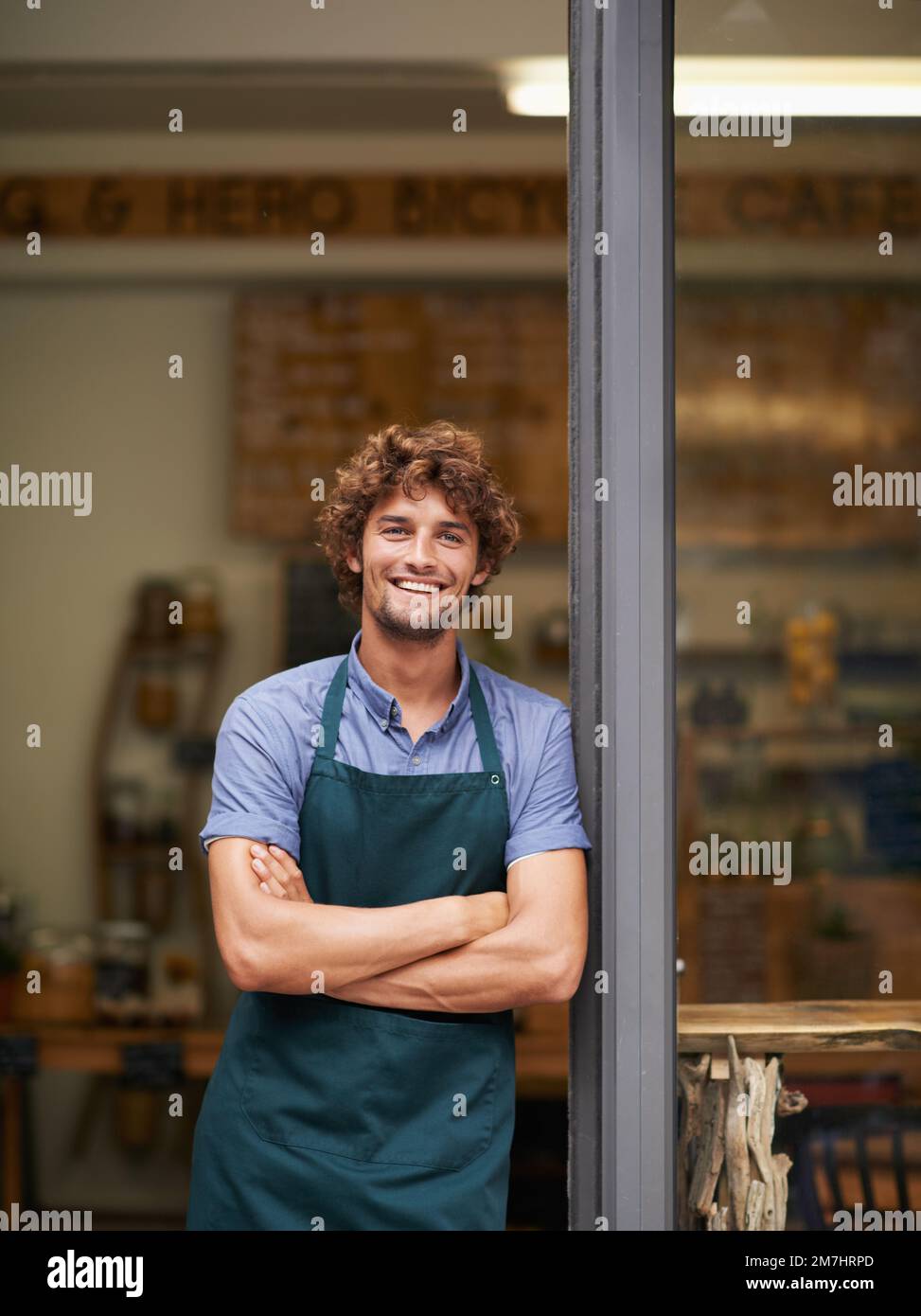Fancy a coffee. A handsome young store owner standing in the entrance ...
