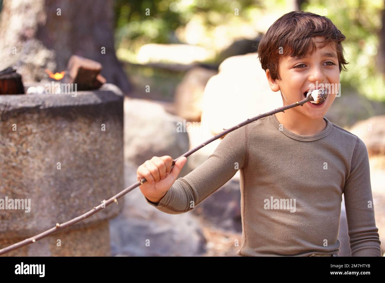 Roasted marshmallows are yummy. A young boy eating a roasted ...