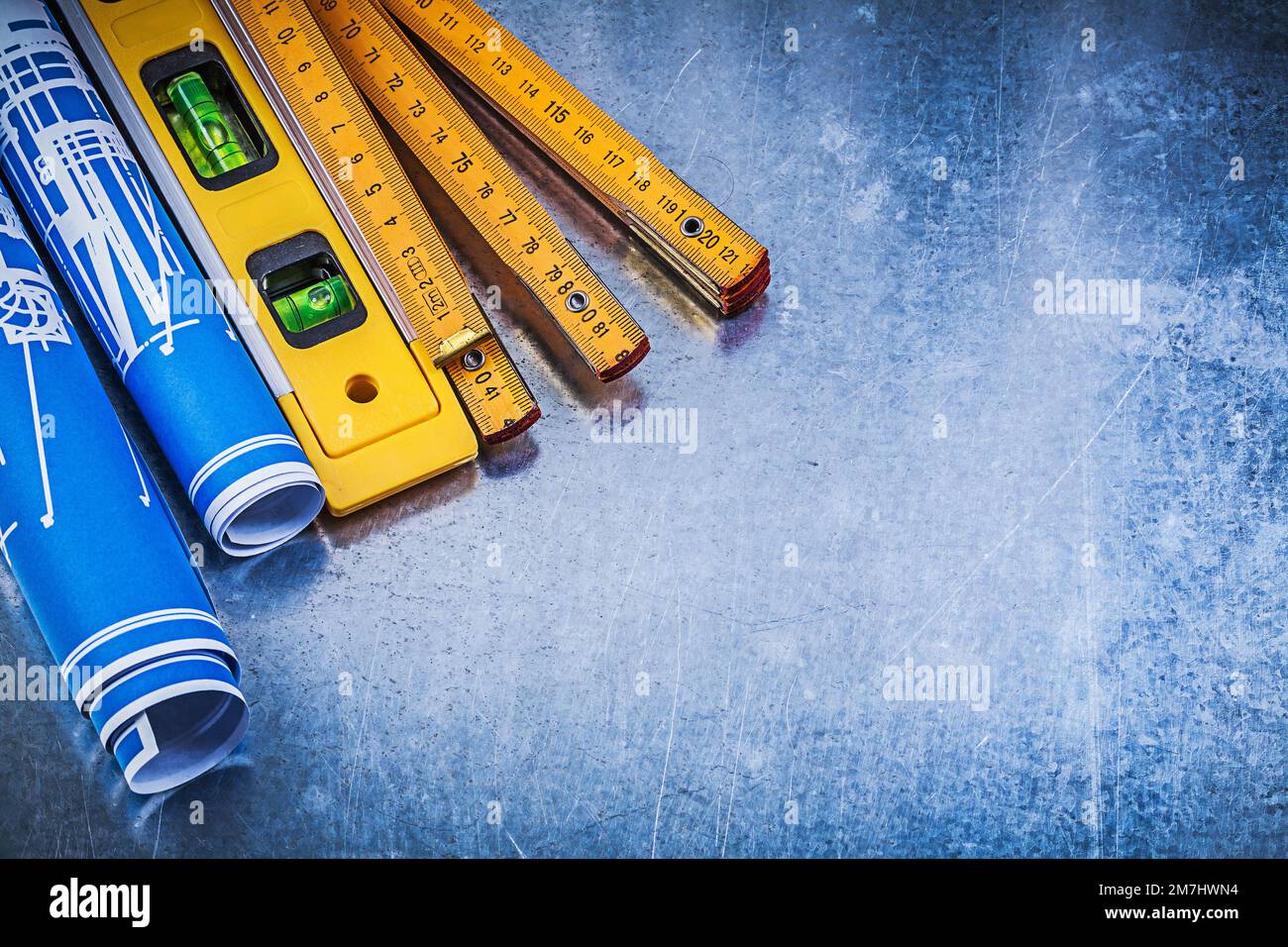Blue rolled blueprints wooden meter construction level on metallic ...