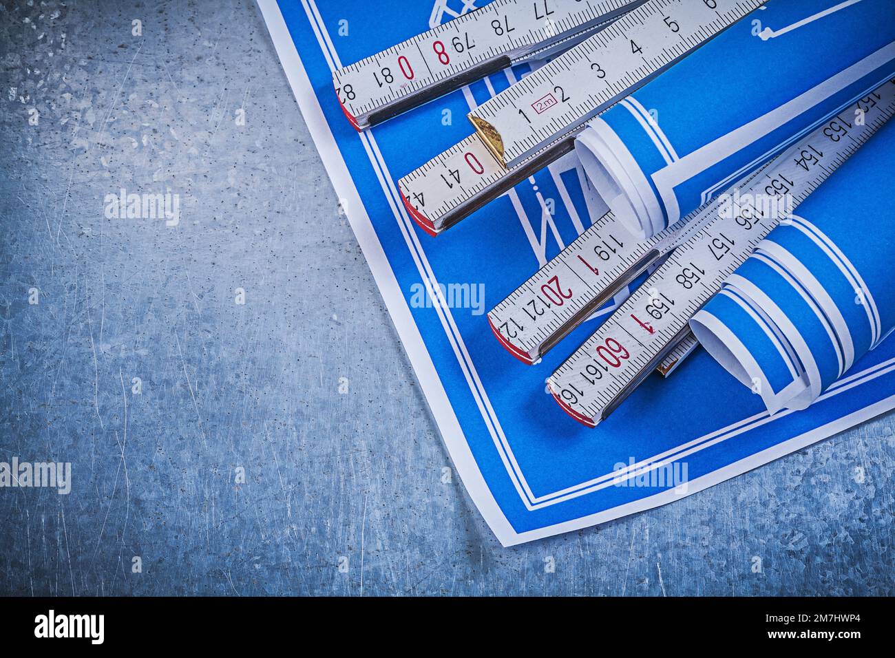 Blue rolled blueprints wooden meter on scratched metallic background ...