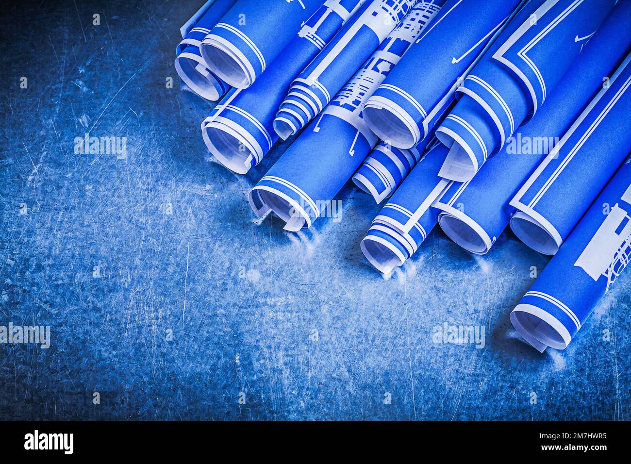 Blue rolled blueprints on metallic background construction concept ...