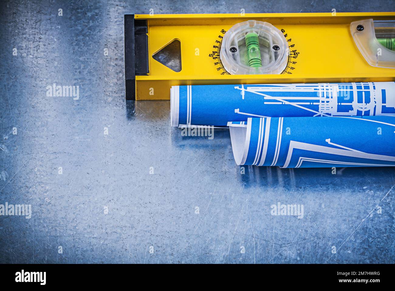 Blue rolled construction drawings level on metallic background ...
