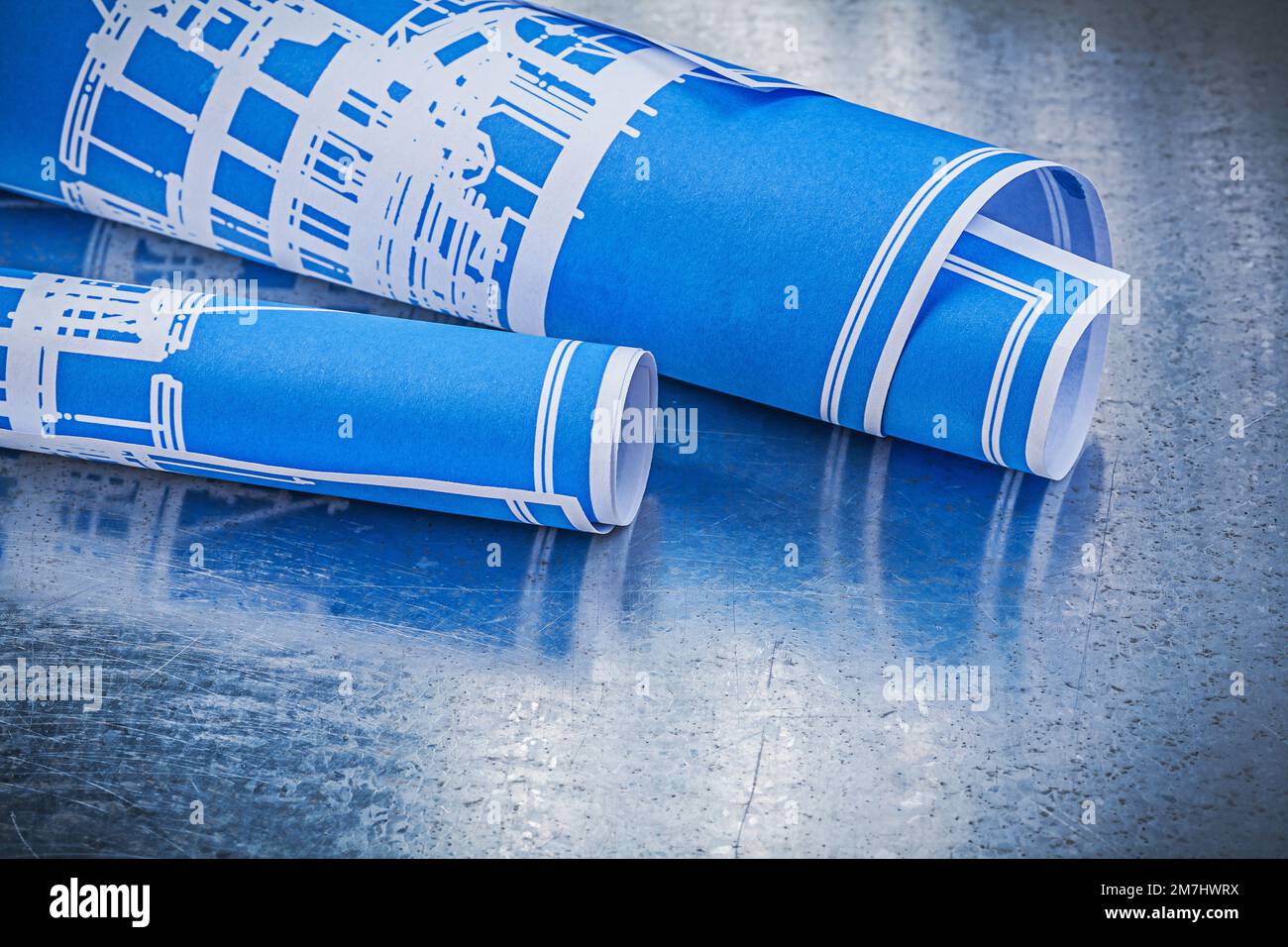 Blue rolled engineering drawings on metallic background construction ...