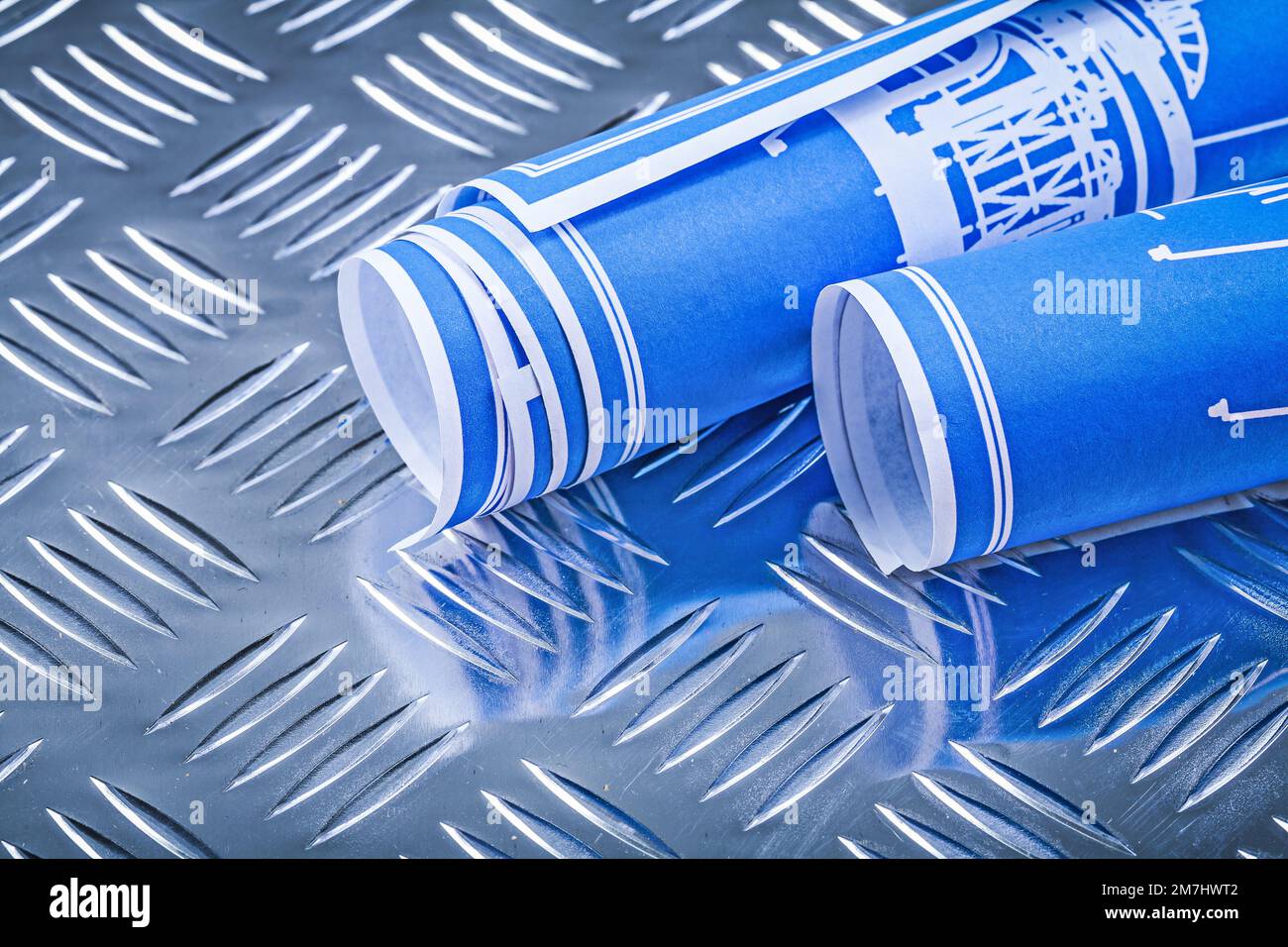 Blue rolled engineering drawings on corrugated metal background ...