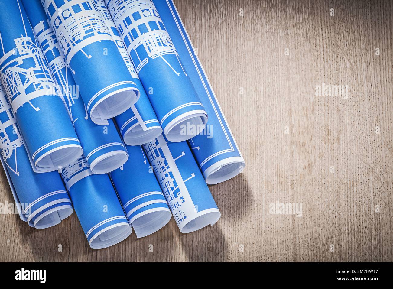 Blue rolled engineering drawings on wooden board directly above ...