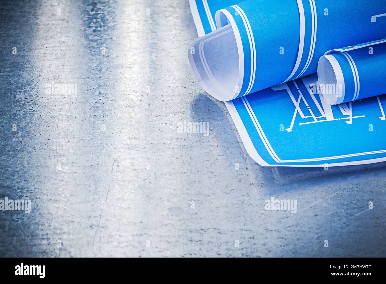 Blue rolled up blueprints on scratched metallic background construction ...