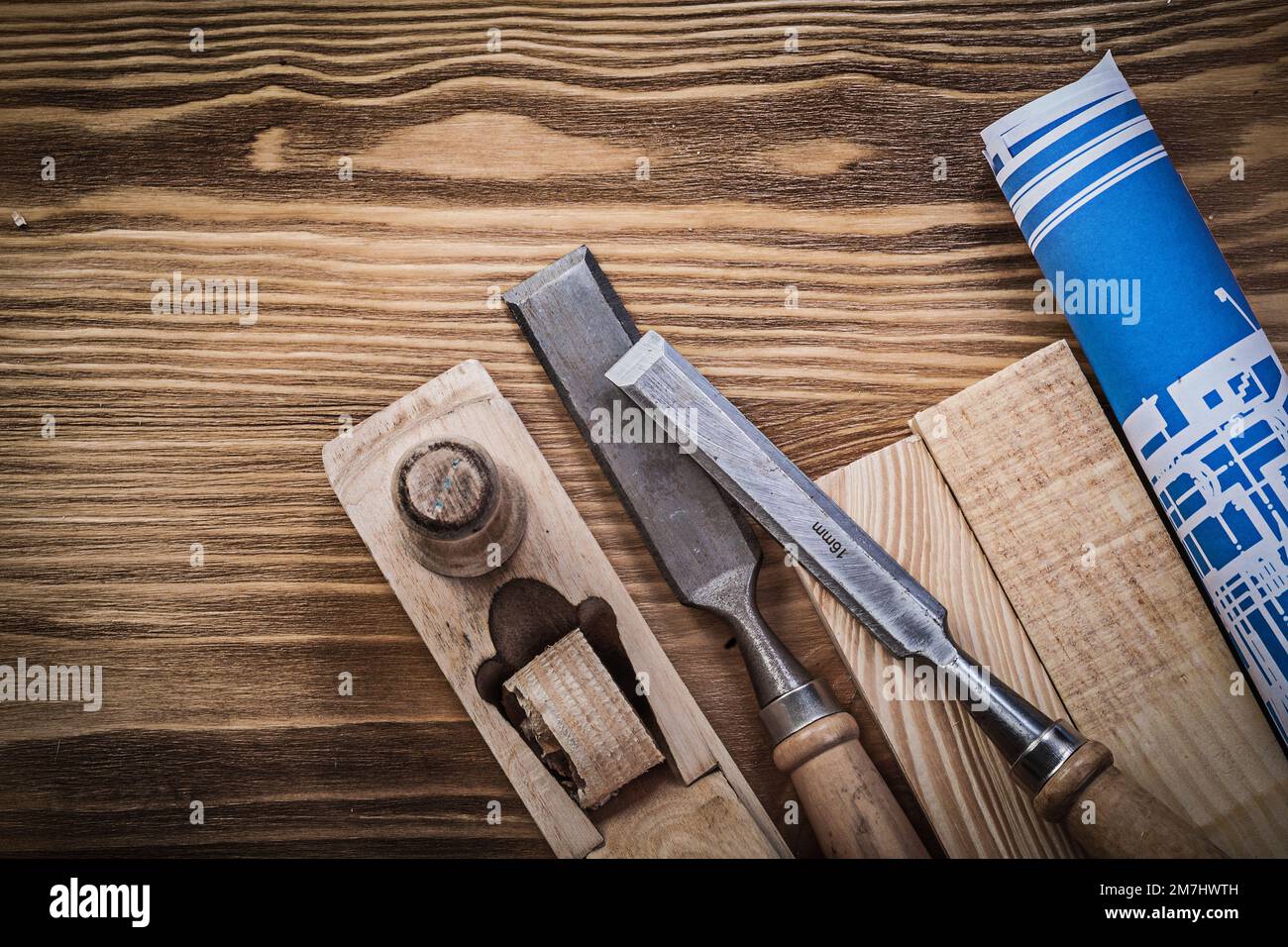 Blue rolled up engineering drawing planer chisels wooden studs on wood ...