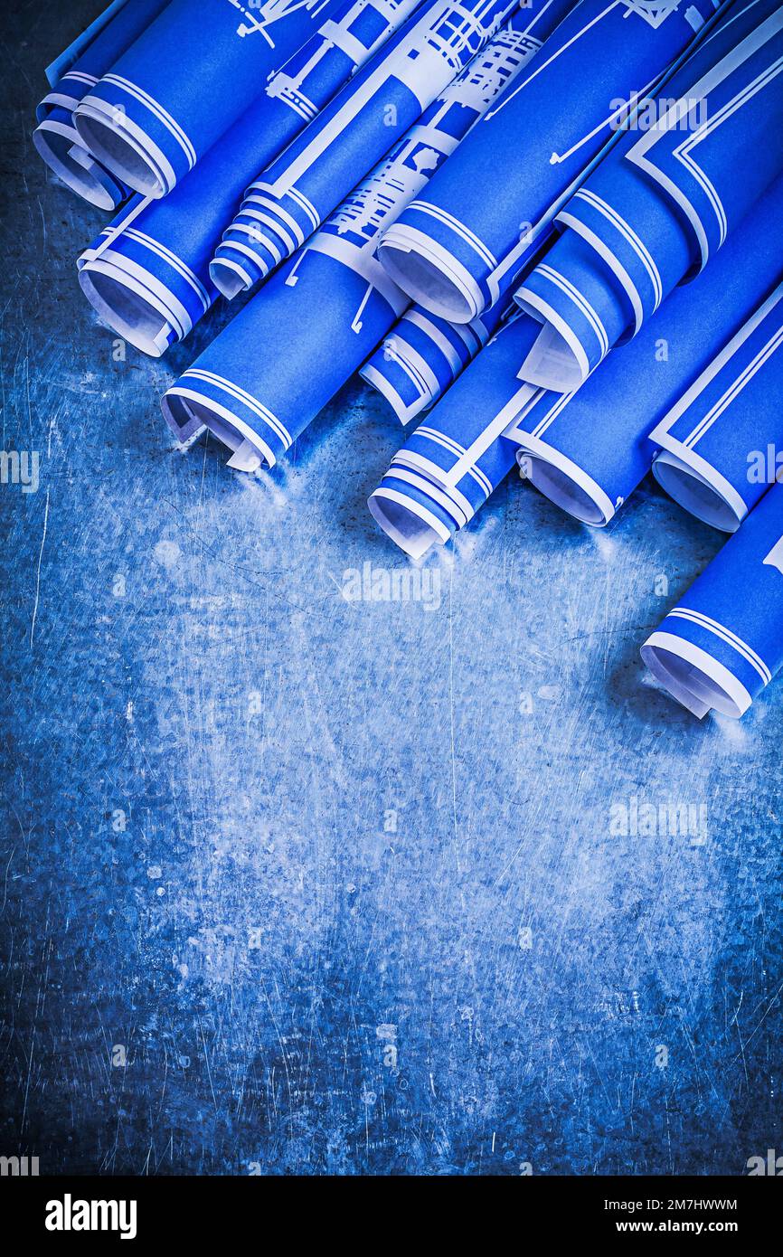 Blue rolled up blueprints on metallic surface construction concept ...