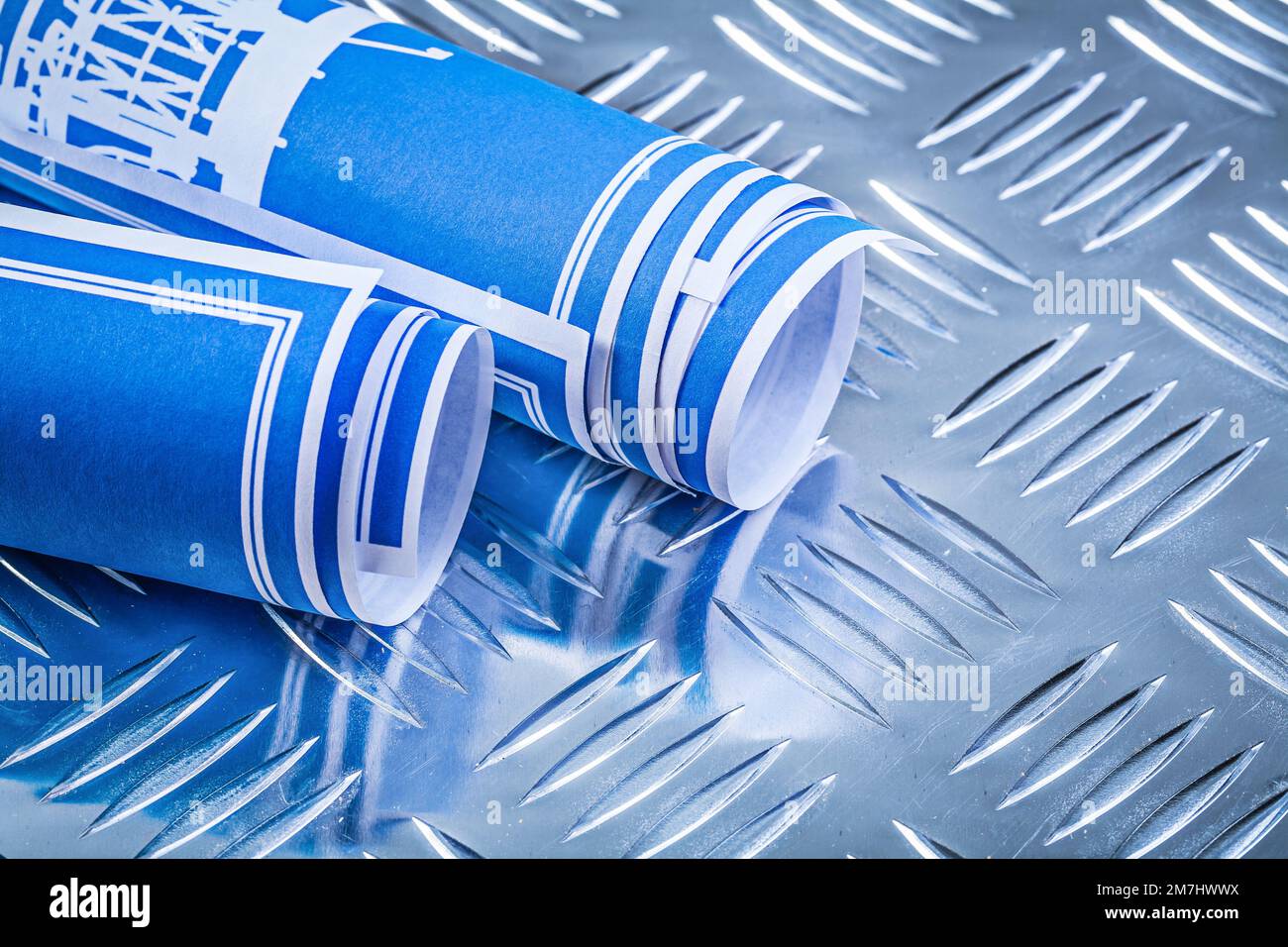 Blue rolled up engineering drawings on fluted metal background ...