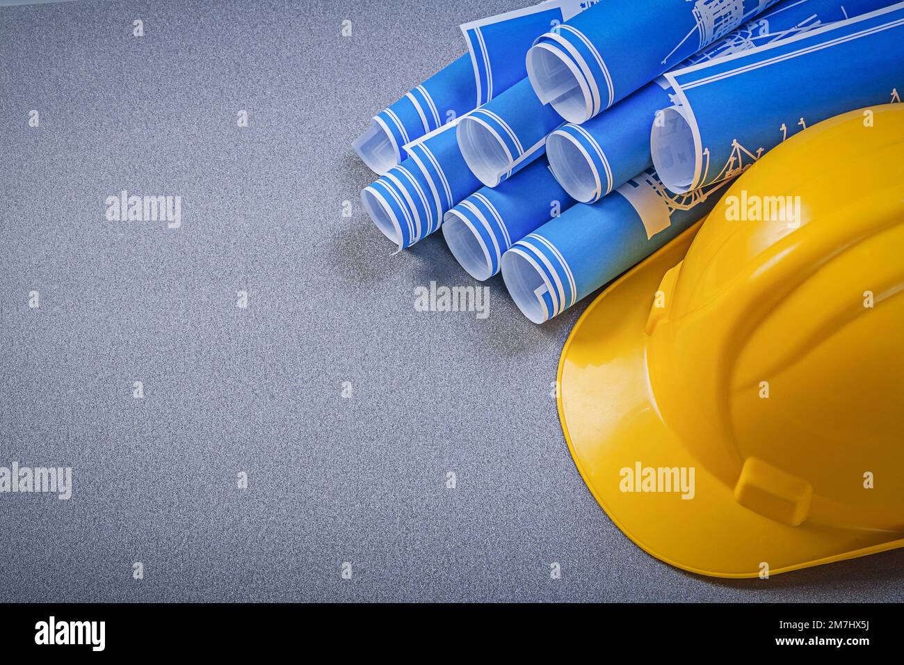 Building helmet blue rolled engineering drawings on grey background ...