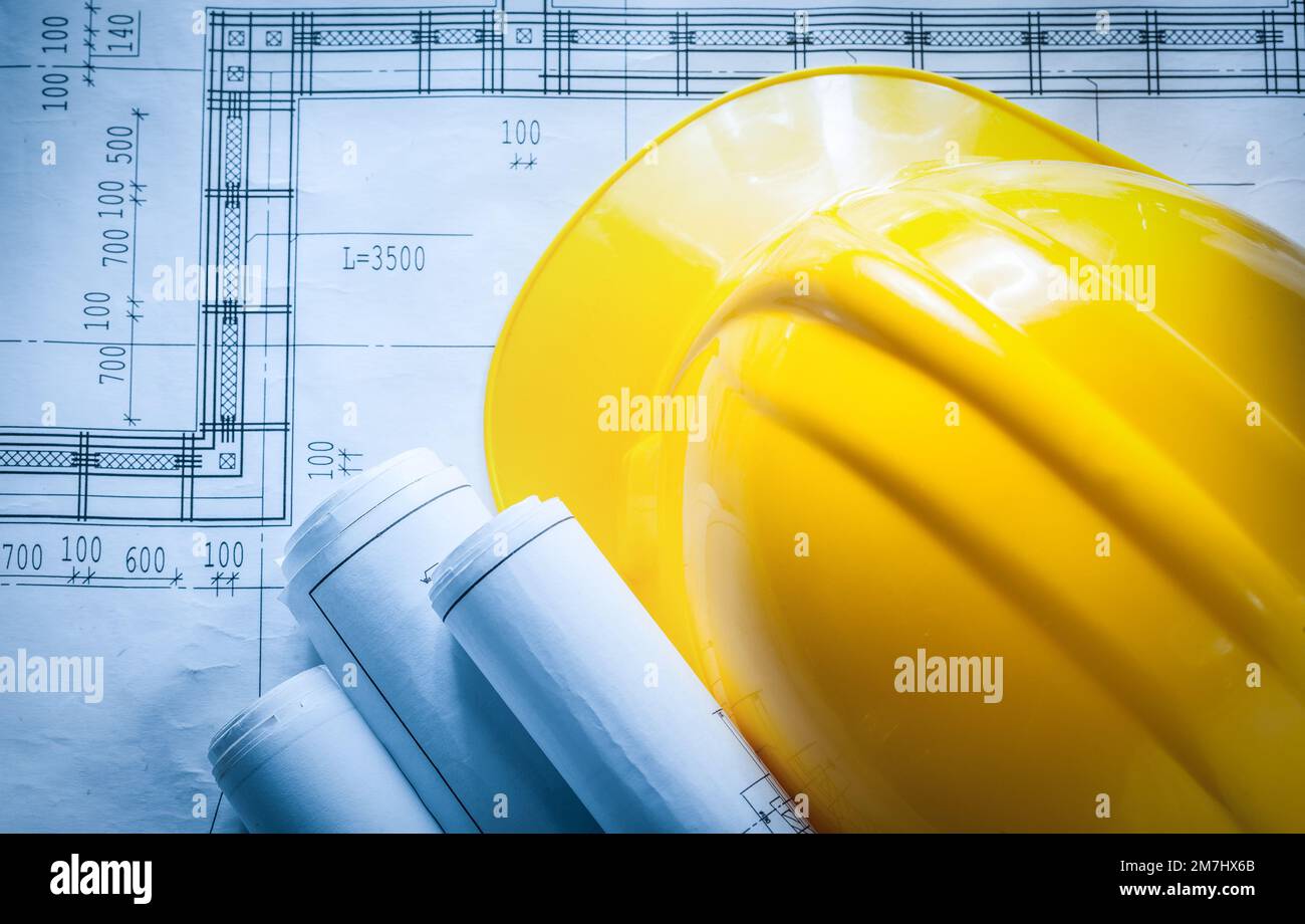 Building helmet rolled construction plans on blueprint Stock Photo - Alamy