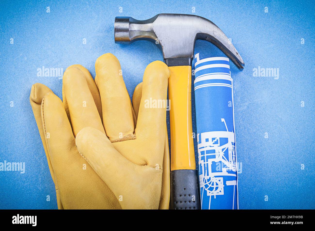 Claw hammer protective gloves rolled up construction drawings on blue ...