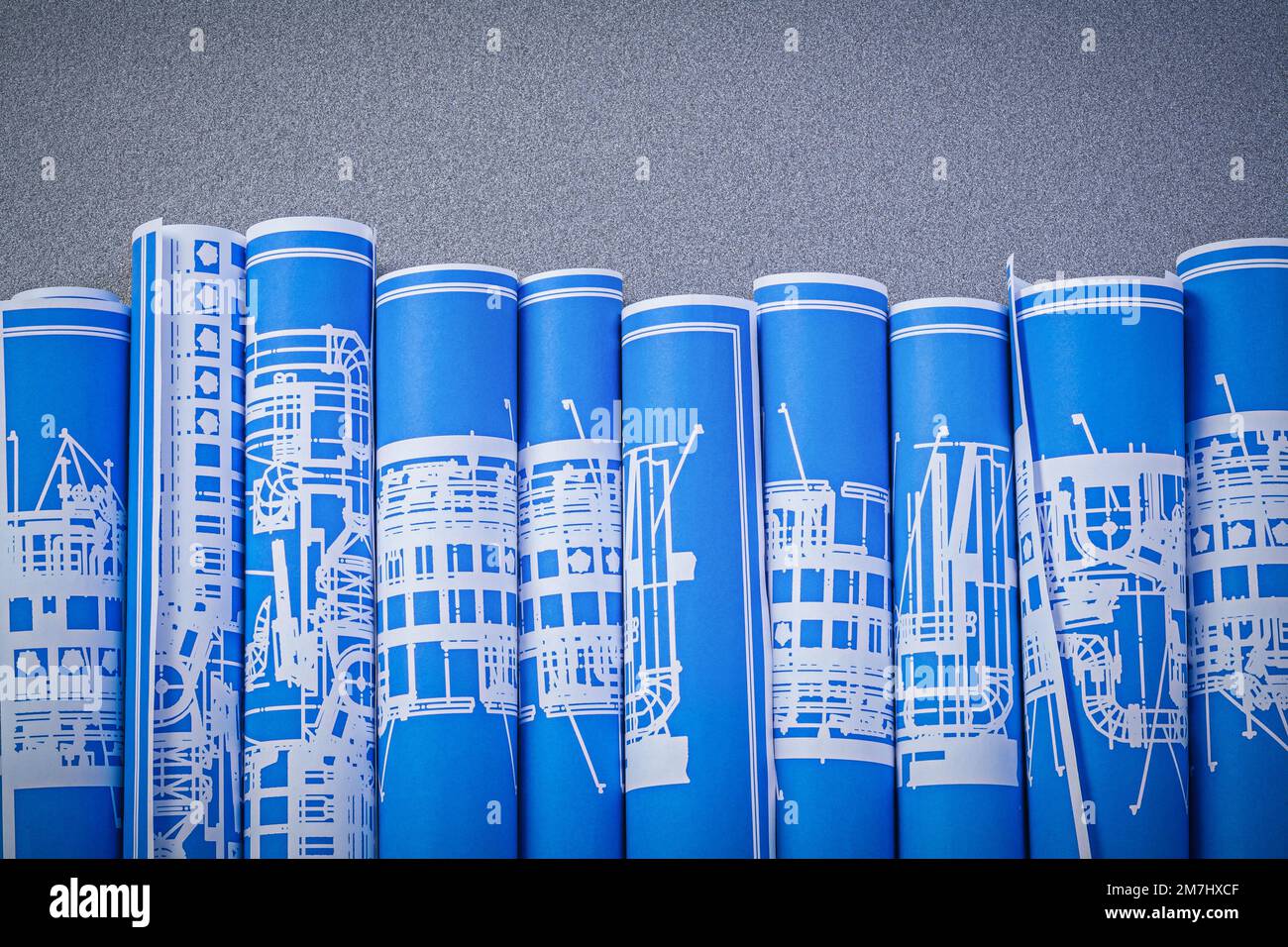 Collection of blue rolled up engineering drawings on grey background ...