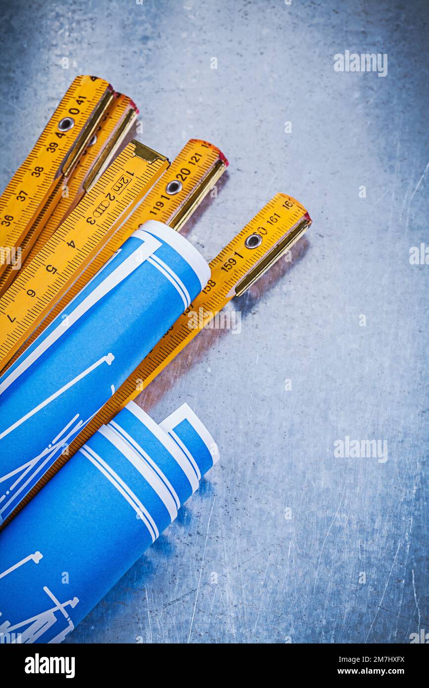 Collection of blue rolled blueprints wooden meter on metallic ...