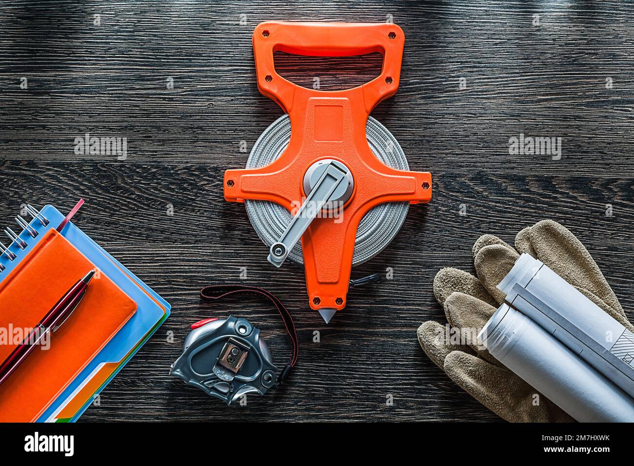 Construction drawings measuring tape safety gloves notepads pen on wood ...