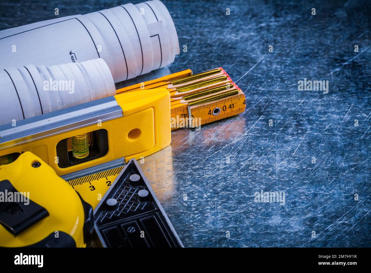 Construction level blueprints and measurement tools on metallic ...