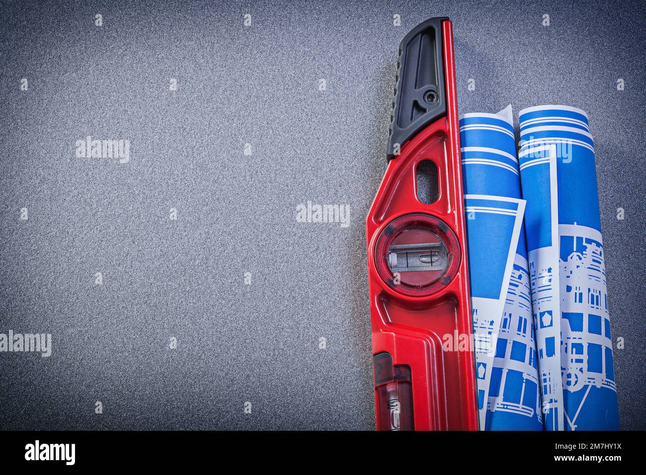 Construction level blue rolled blueprints on grey background copy space ...