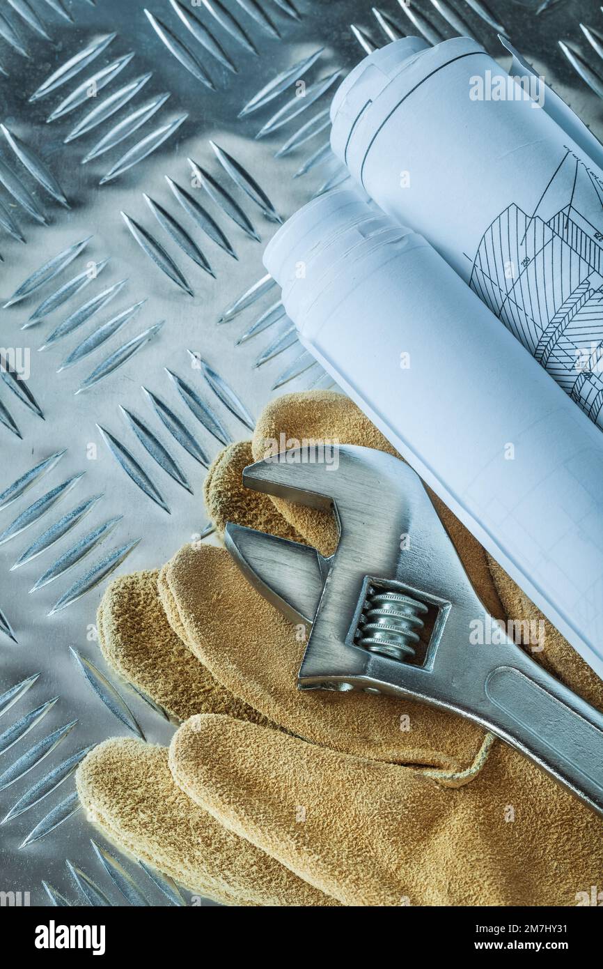 Construction plans adjustable wrench protective gloves on fluted metal ...