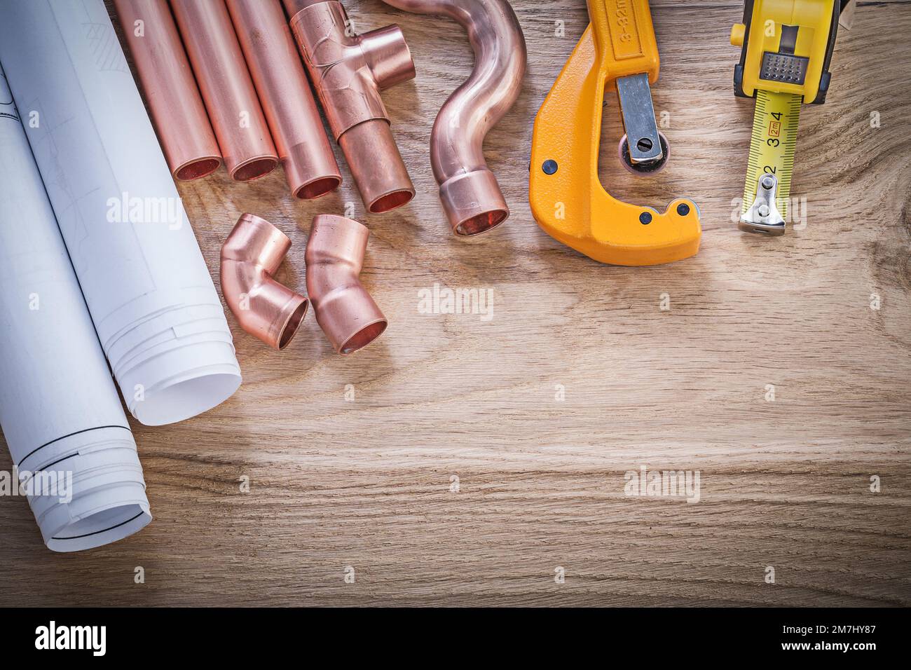 Construction plans tape line water pipe cutter fittings on wood board ...
