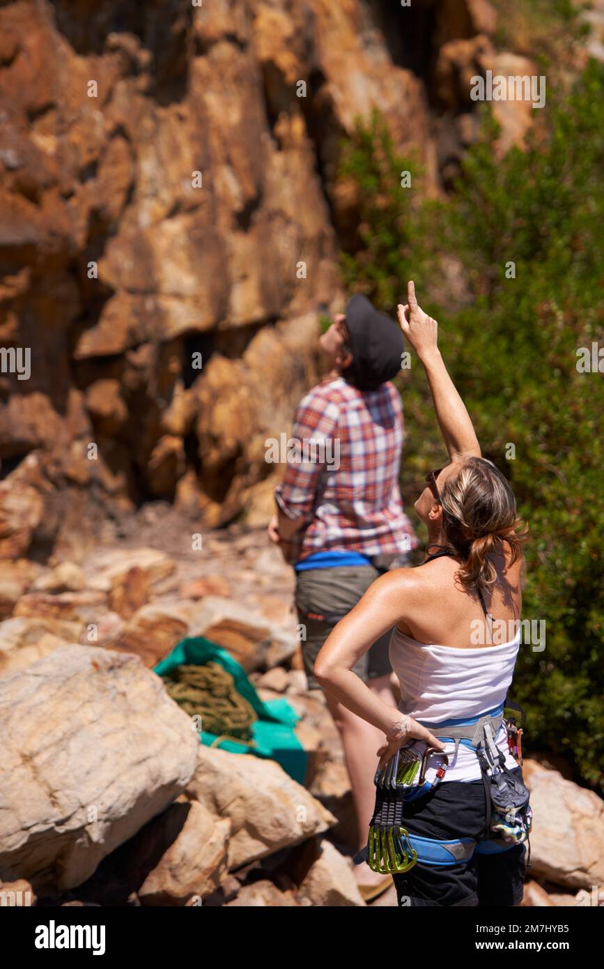 To scale a mountain. Two rock climbers deciding on which route to take ...