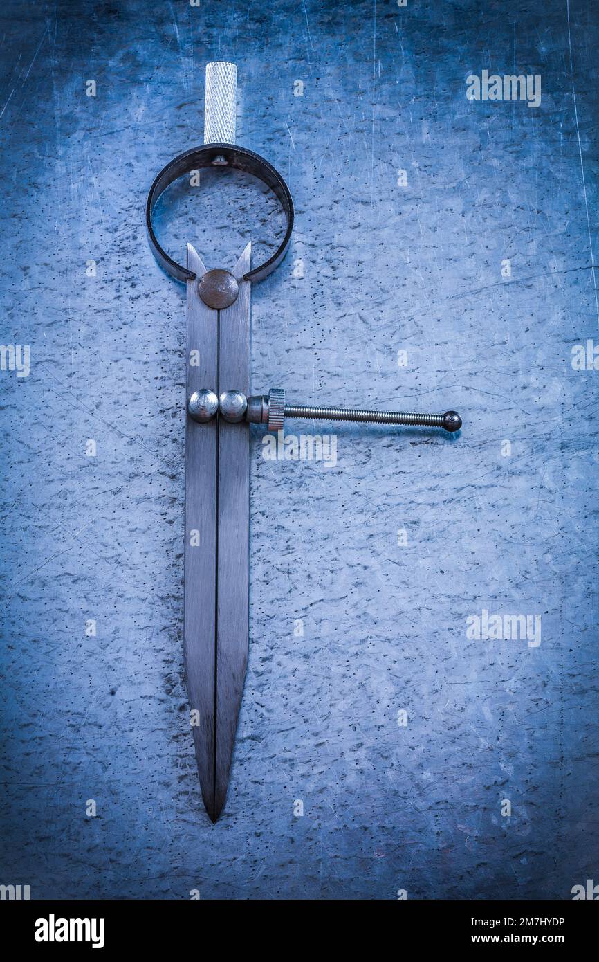 Drawing compass on scratched metallic background construction concept ...