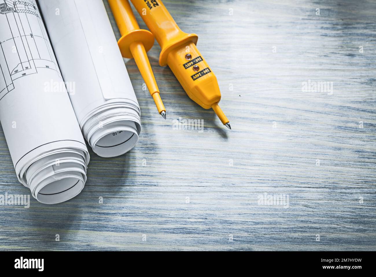 Electric tester rolled construction drawings on wooden board ...