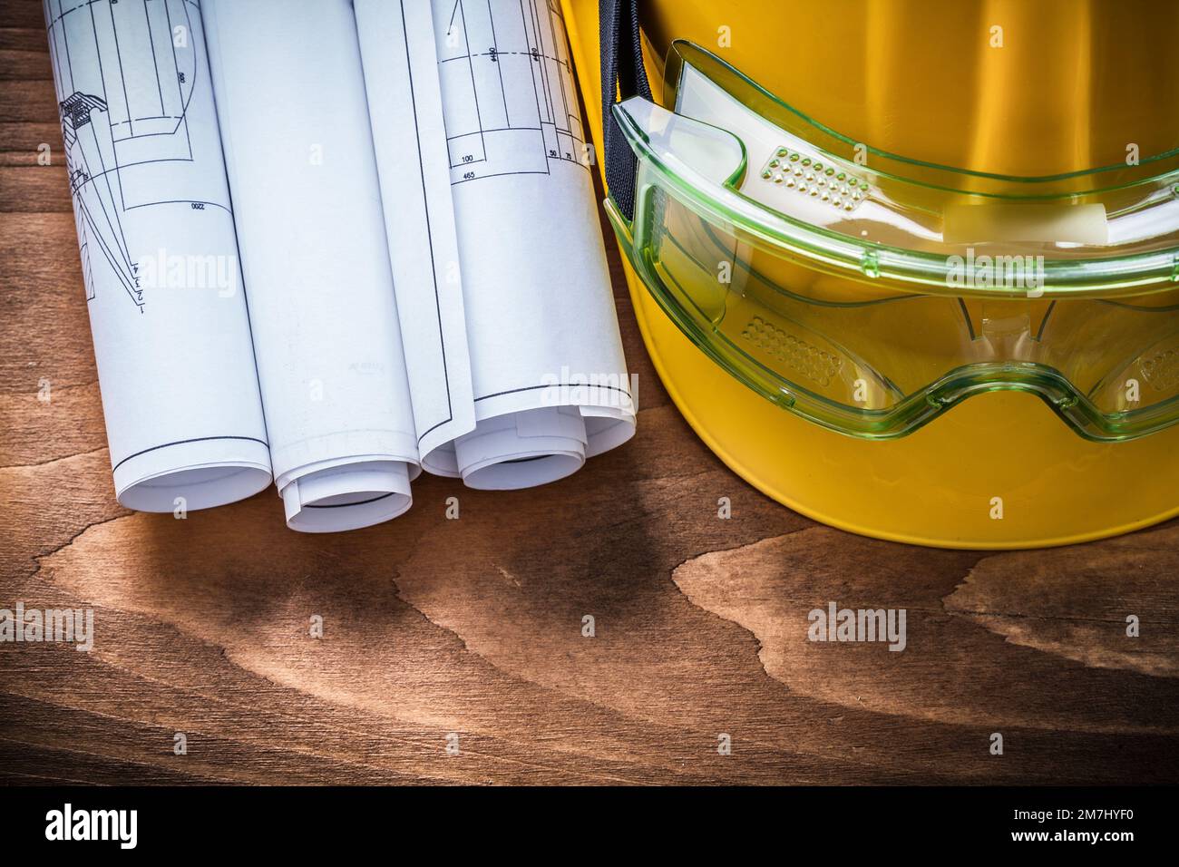 Goggles blueprint rolls and hard hat on brown wood board Stock Photo ...