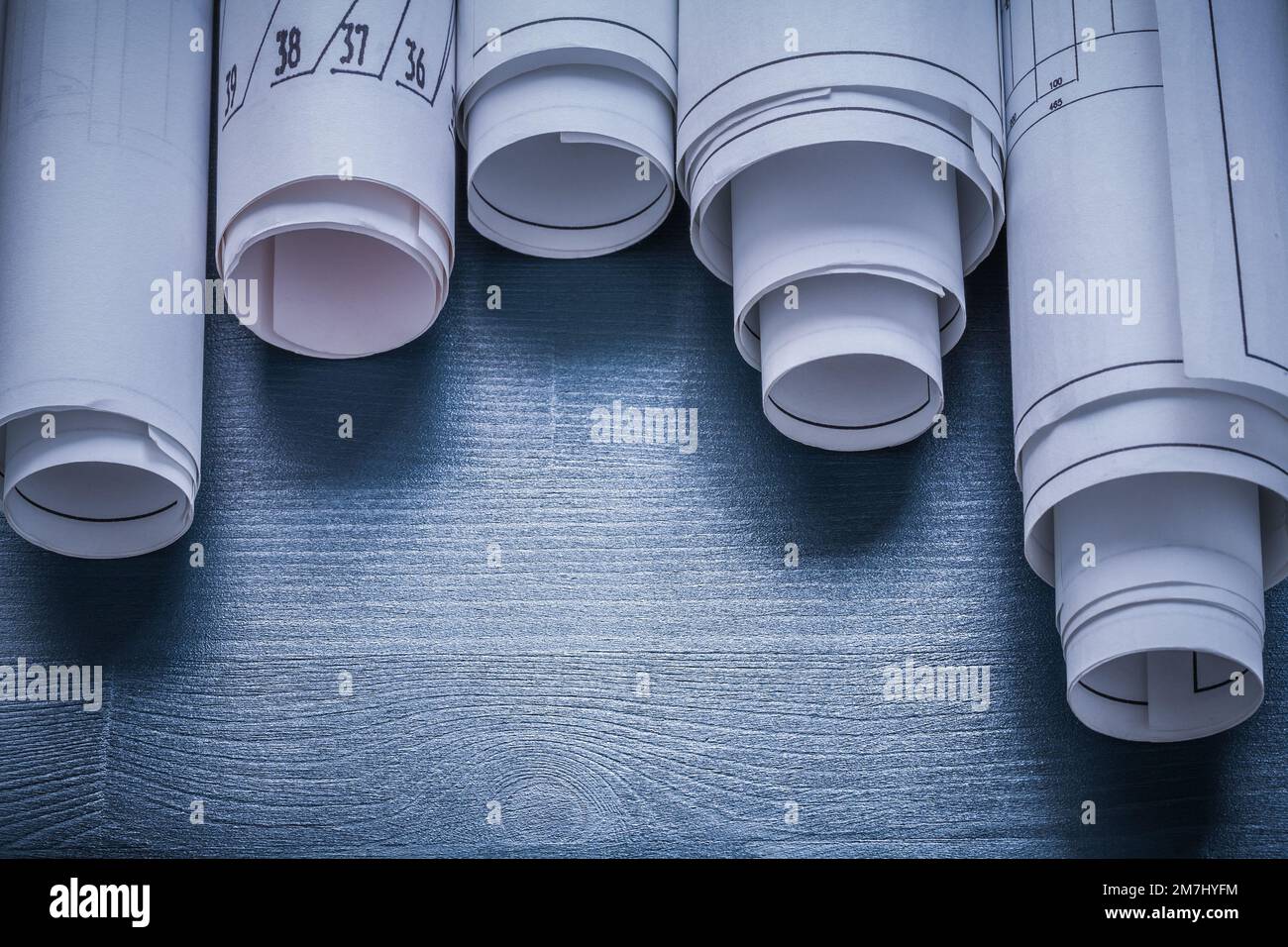 five blueprints rolled up on blue board Stock Photo - Alamy