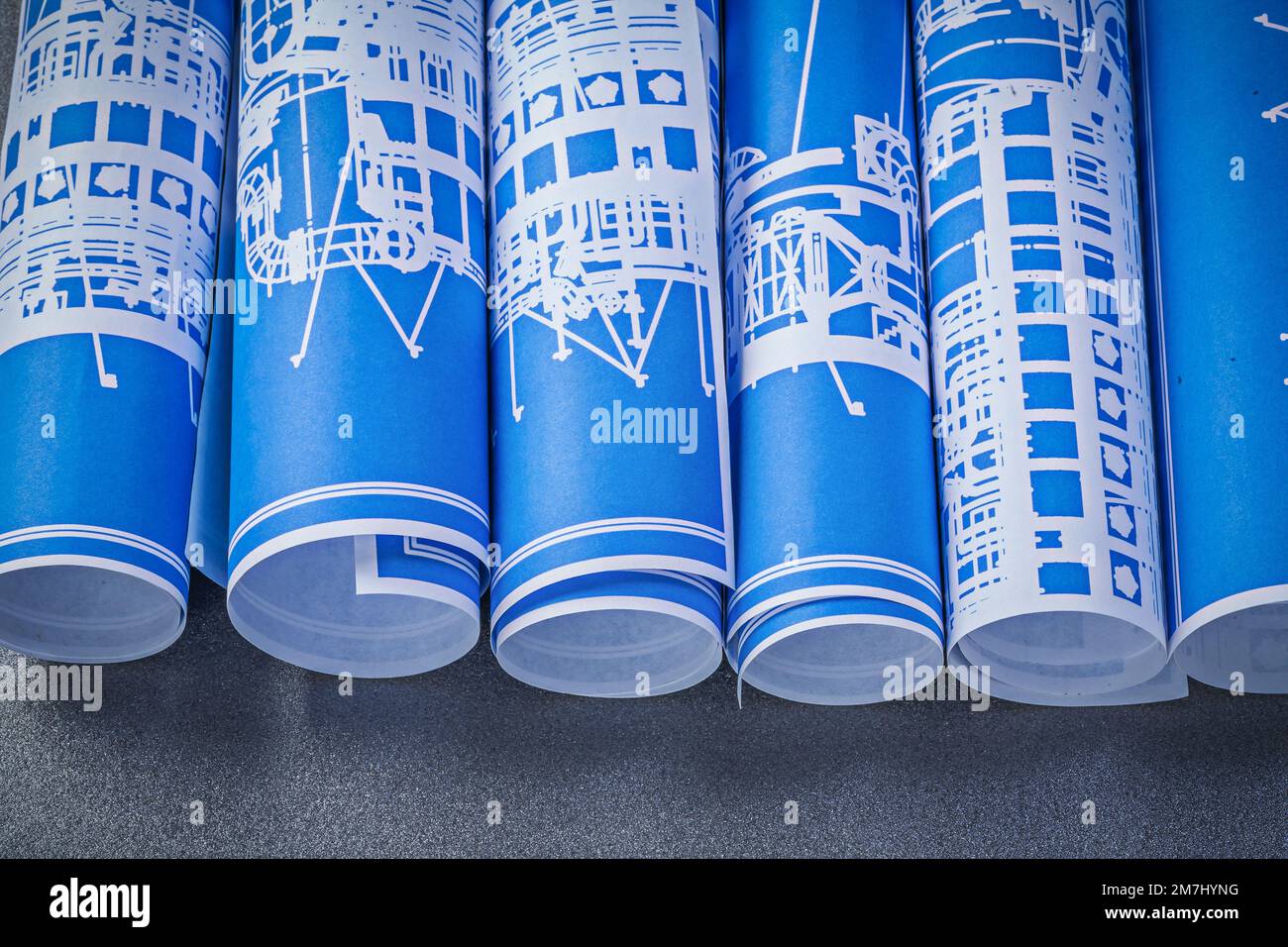 Heap of blue rolled engineering drawings on grey background ...