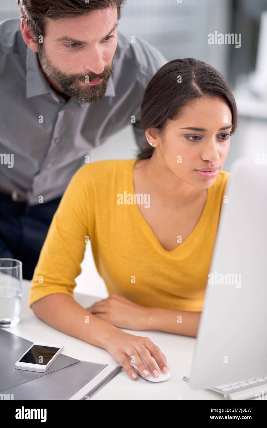 Teamwork gets the job done. Two colleagues working together in front of a computer Stock Photo ...