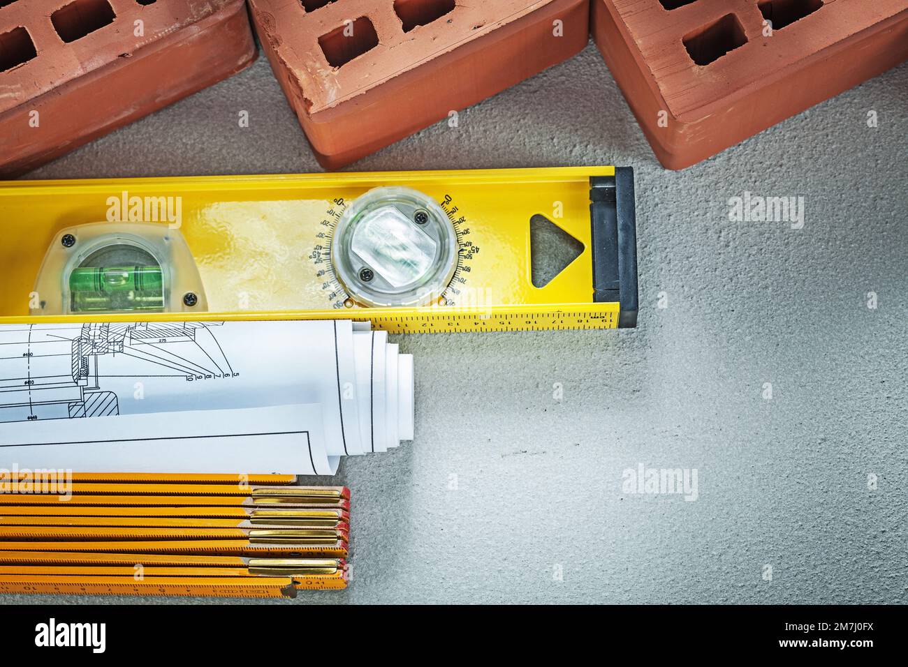 Red bricks construction level wooden meter blueprints on concrete ...