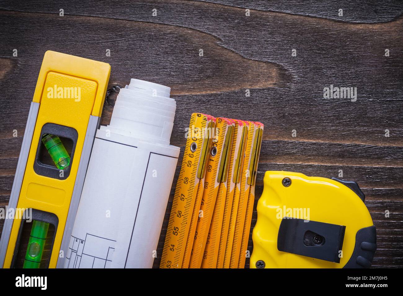 Roll of blueprints construction level tape-line and wooden meter on ...