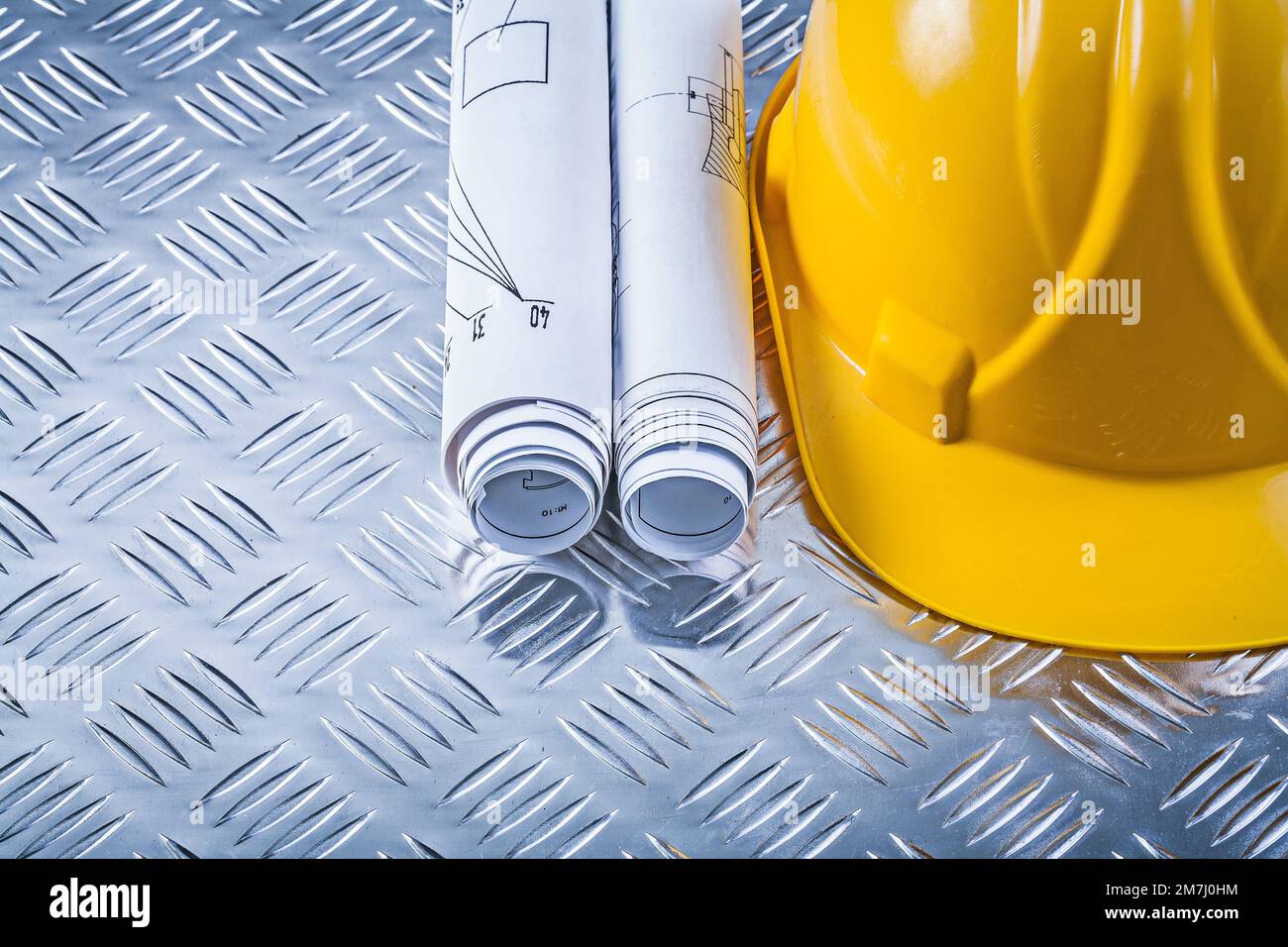 Rolled blueprints building helmet on grooved metal sheet construction ...