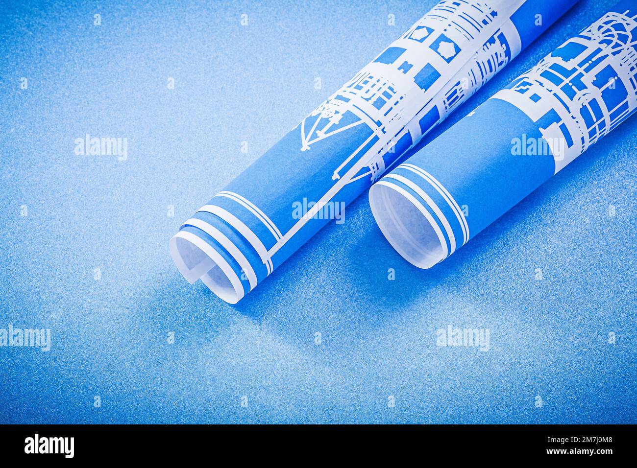 Rolled blueprints on blue background construction concept Stock Photo ...