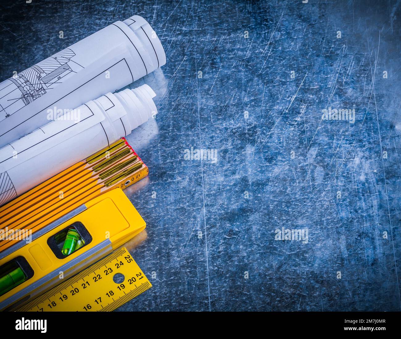 Rolled blueprints ruler construction level and wooden meter on metallic ...