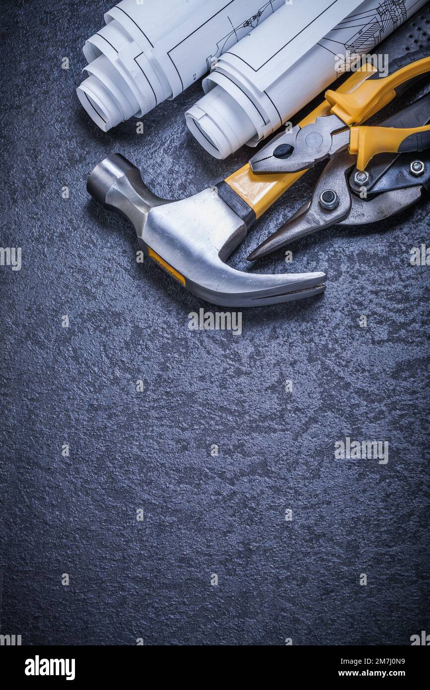 Rolled blueprints tin snips pliers claw hammer on black background ...