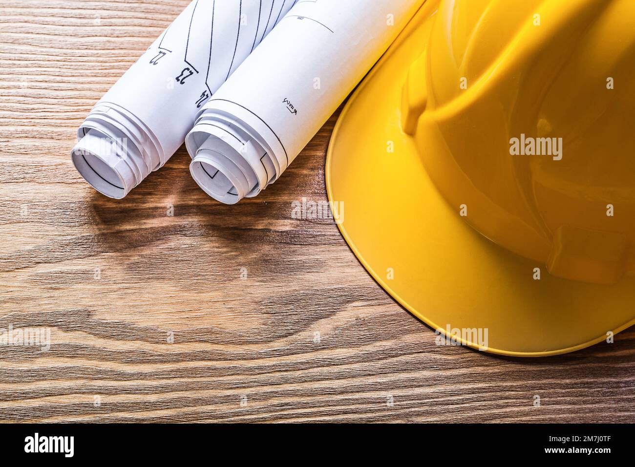 Rolled engineering drawings hard hat on wooden board construction ...