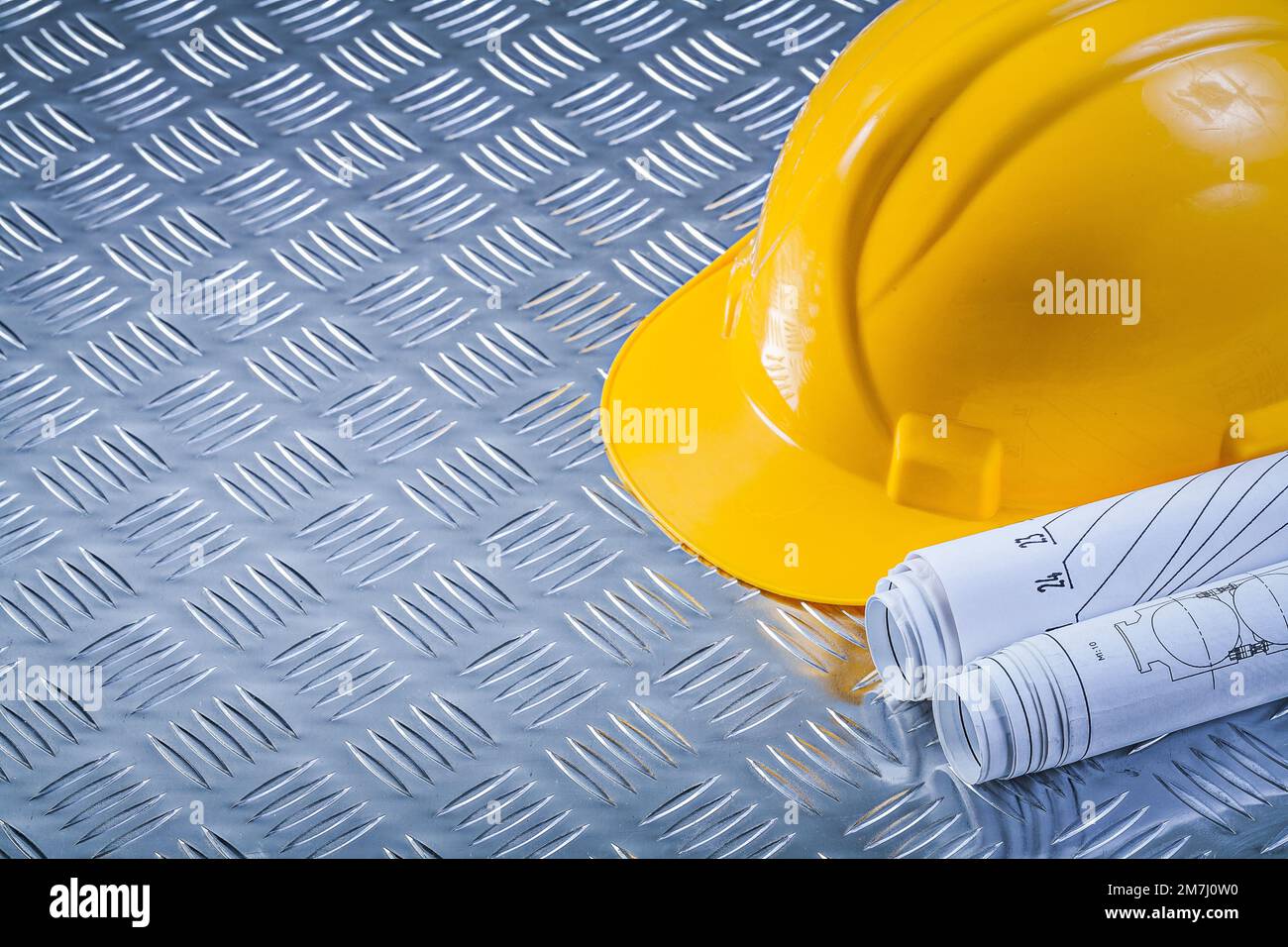 Rolled engineering drawings hard hat on fluted metal background ...
