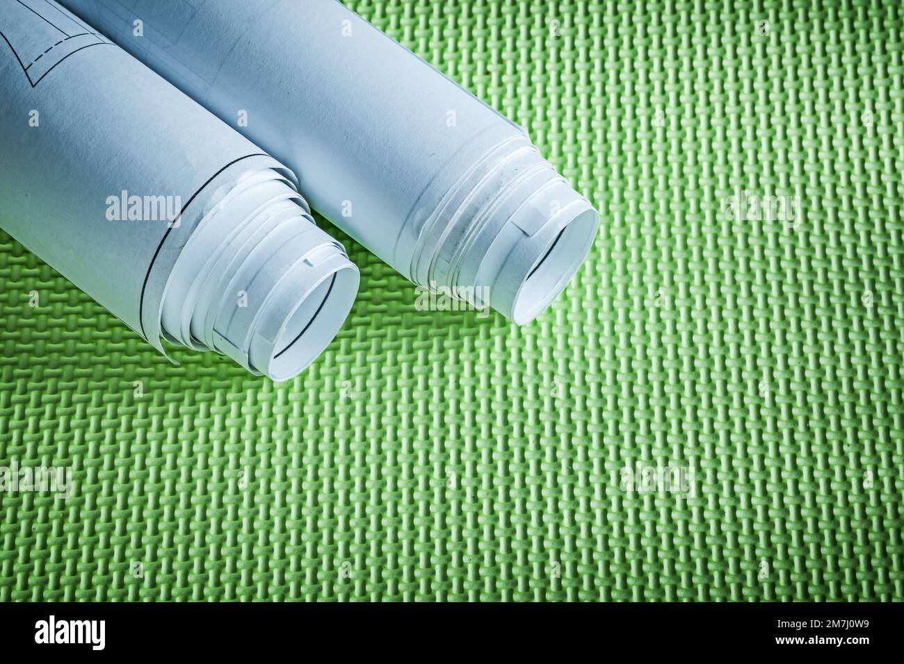 Rolled engineering drawings on green background construction concept ...