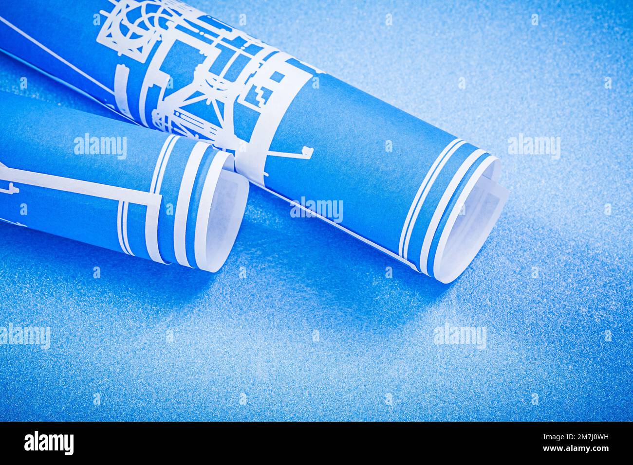 Rolled engineering drawings on blue background construction concept ...