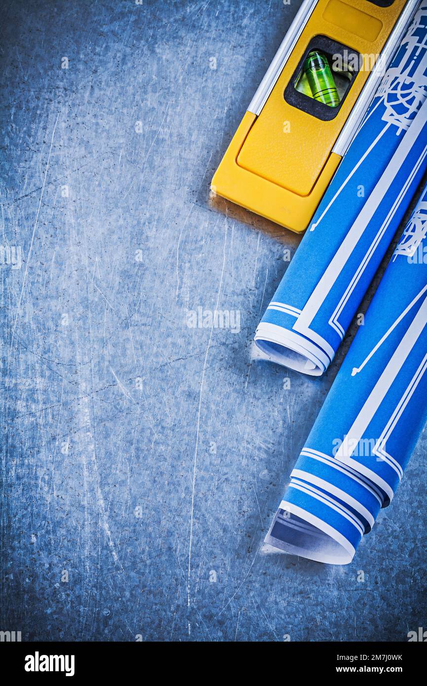 Rolled up blue blueprints construction level on metallic background ...