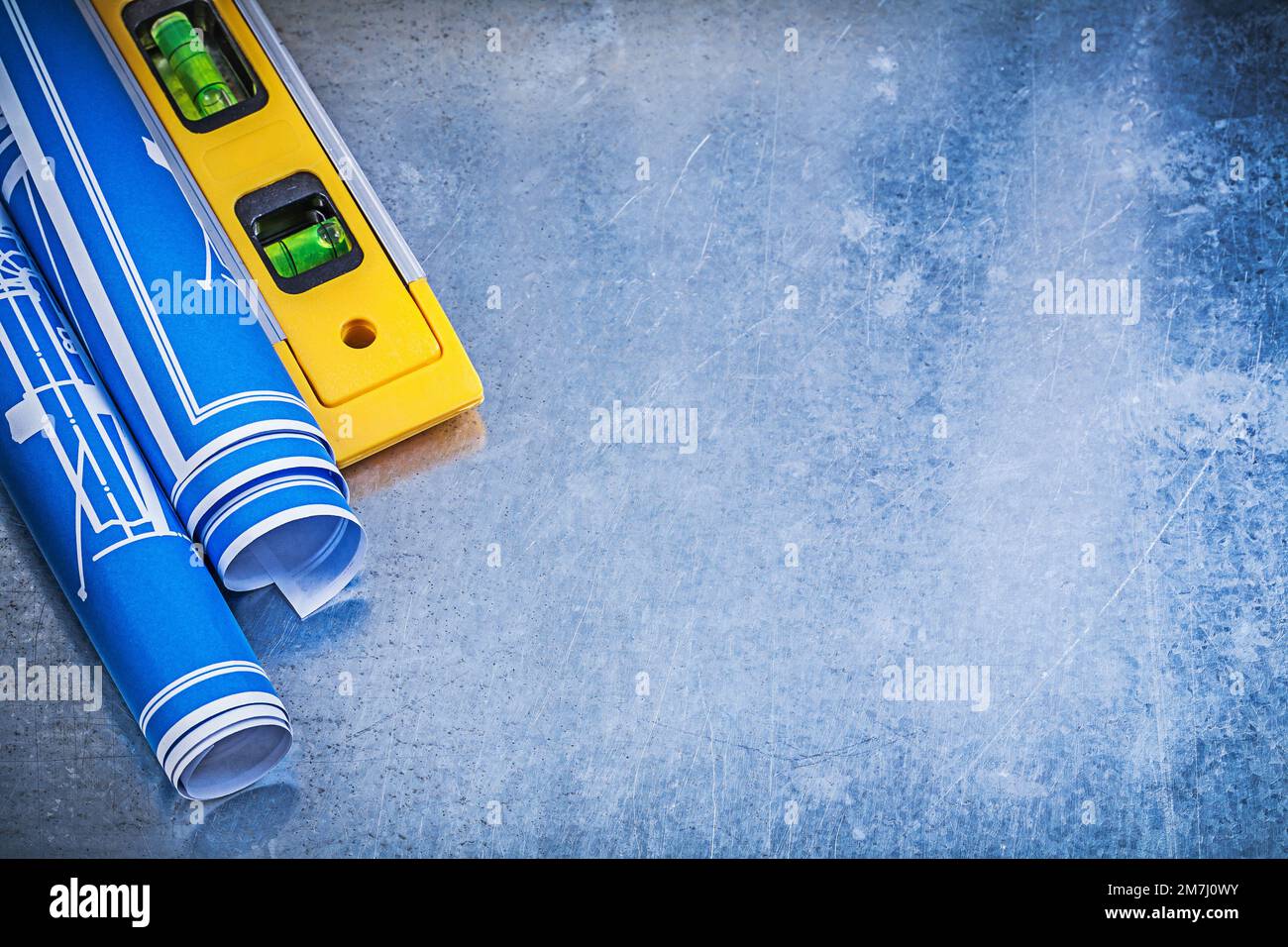 Rolled up construction drawings level on metallic background Stock ...